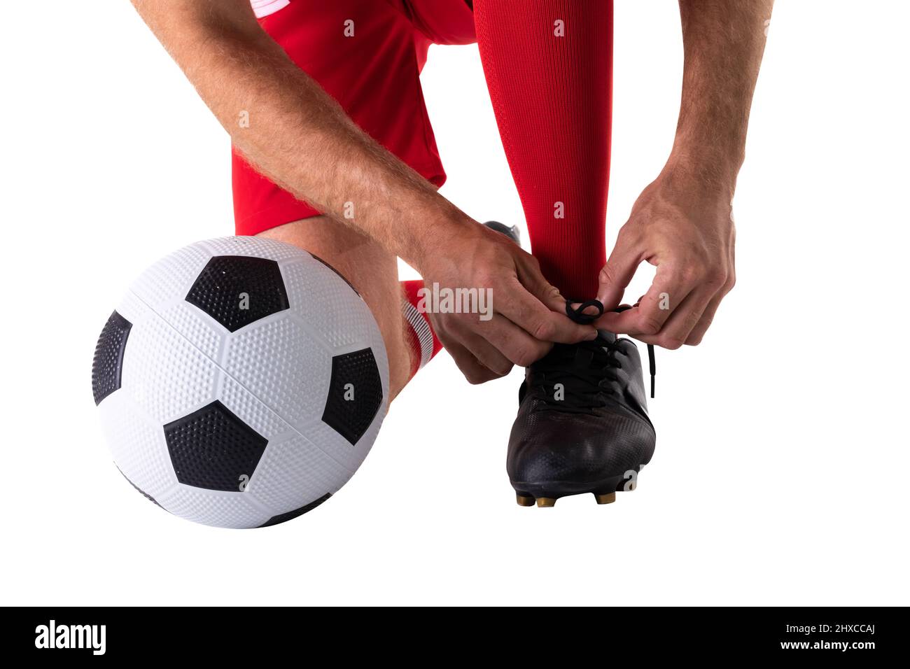 Low section of young male caucasian athlete tying shoelace by soccer ...