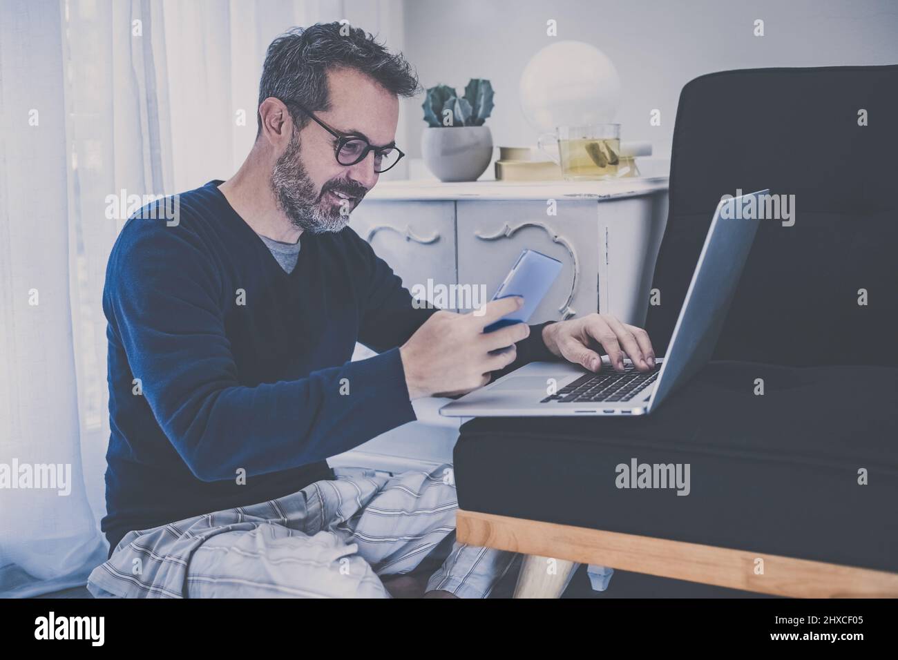 Man works with laptop sitting on the ground at home. Male working at ...
