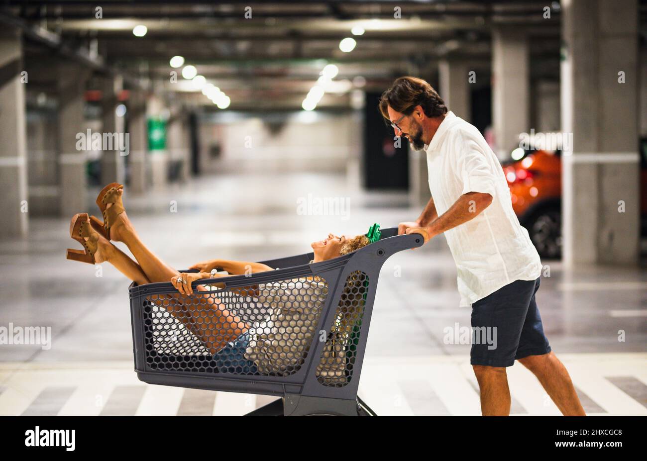 Underground parking, man, shopping cart, woman, push, fun Stock Photo ...