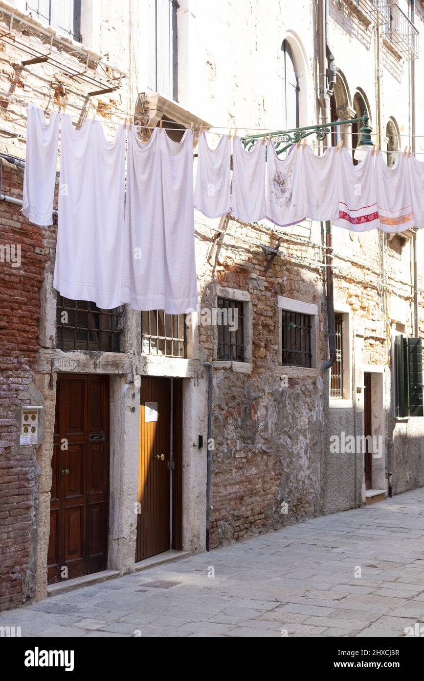 White laundry on a taut clothesline between houses in a narrow alley in ...