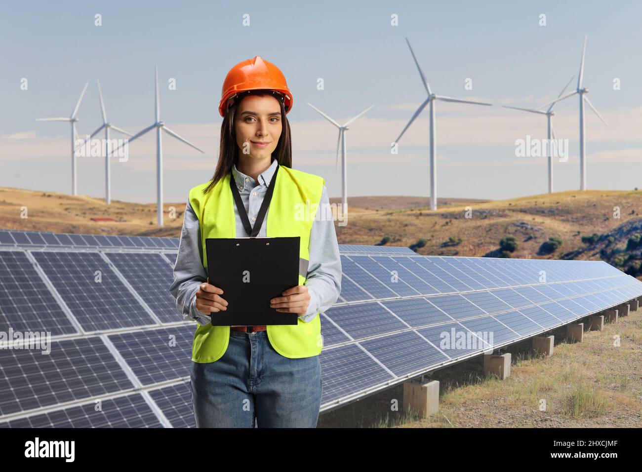 Young female engineer on a renewable energy field with wind turbines ...