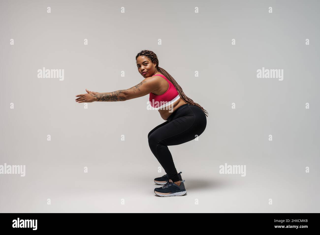 Proud young african bodypositive fitness woman over gray wall ...