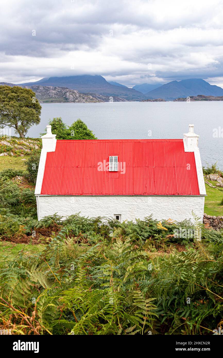A small croft with a red corrugated iron roof on the banks of Loch ...