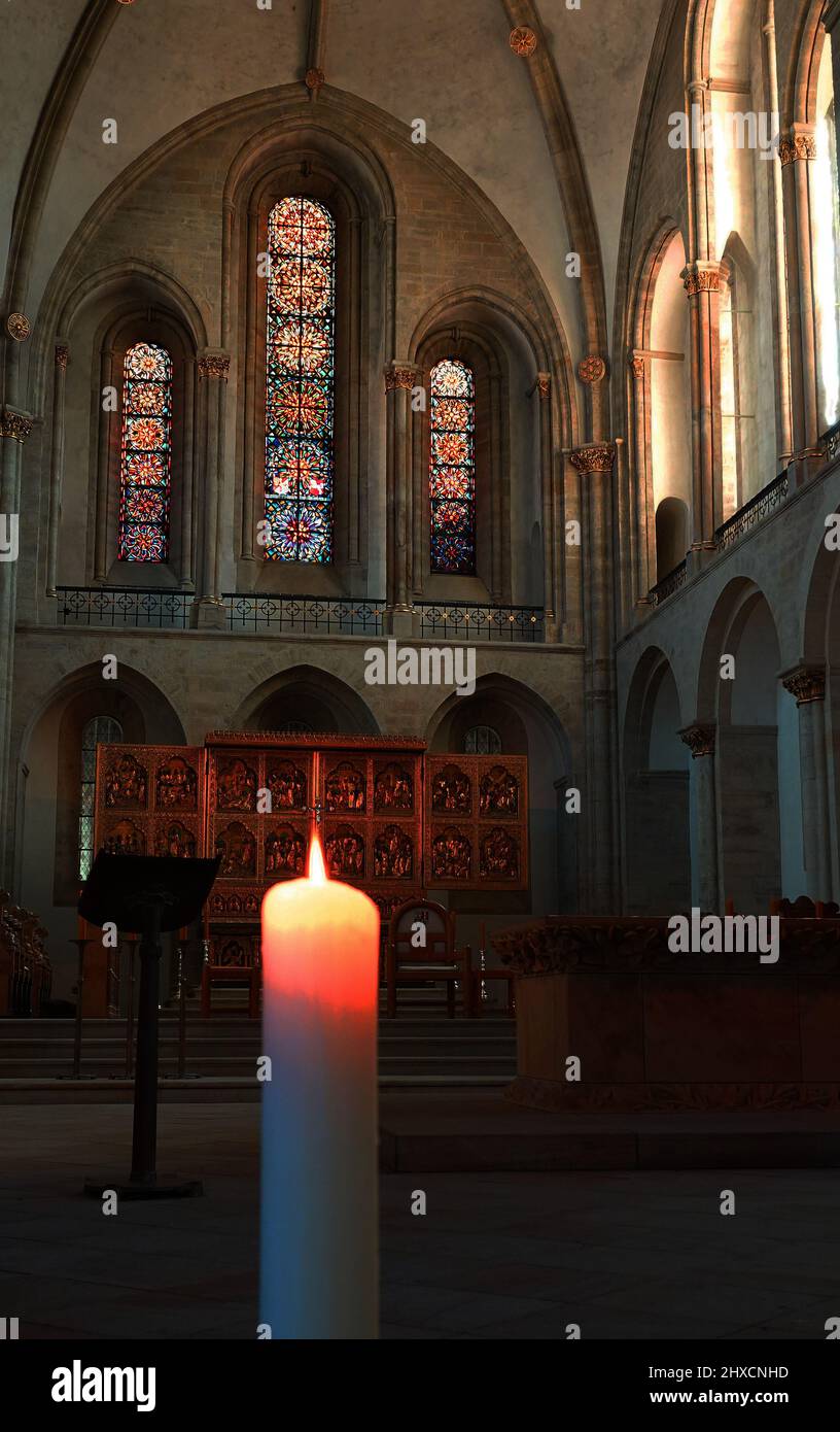 Interior of a church: a burning candle, an altar and stained glass ...