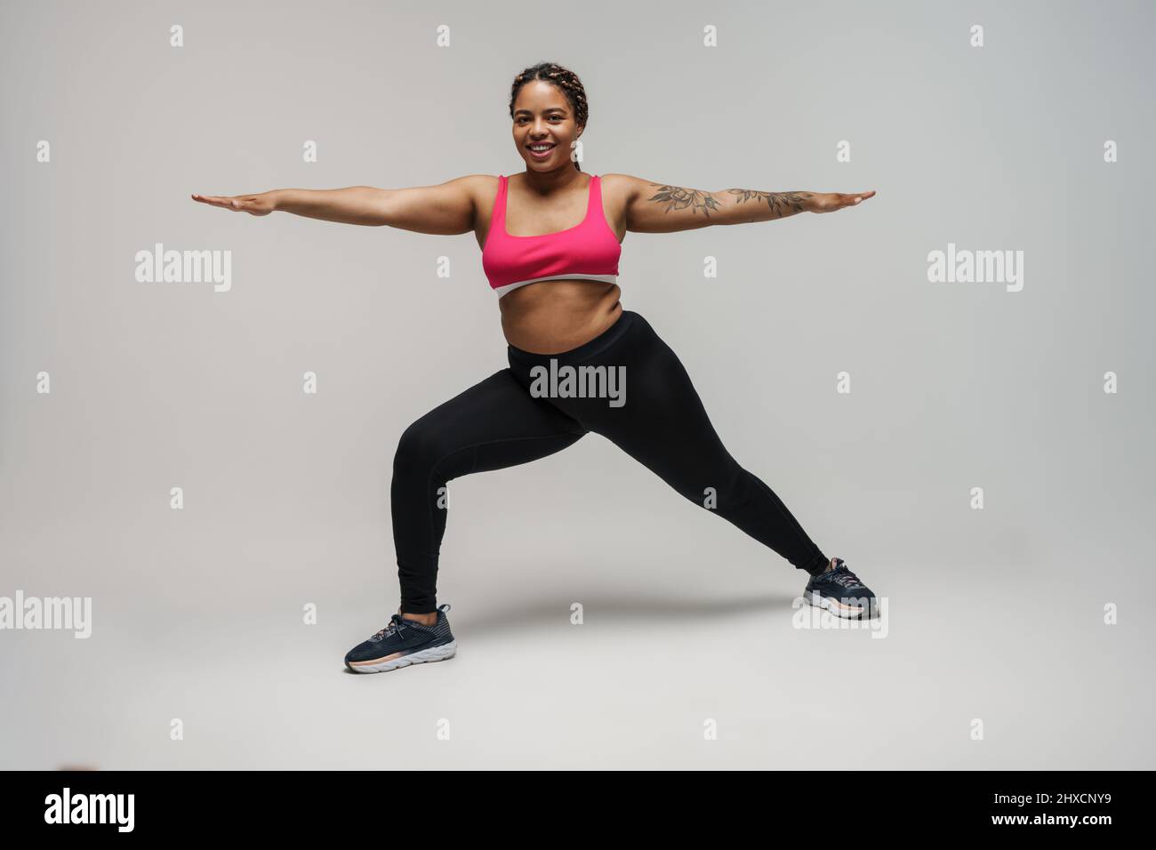 Smiling young african bodypositive fitness woman over gray wall ...