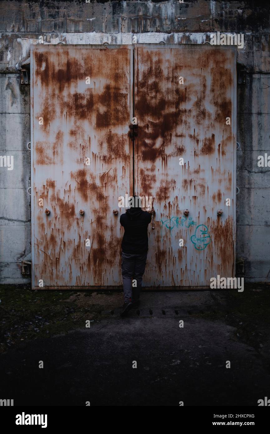 Person pulling on huge rusty door Stock Photo - Alamy