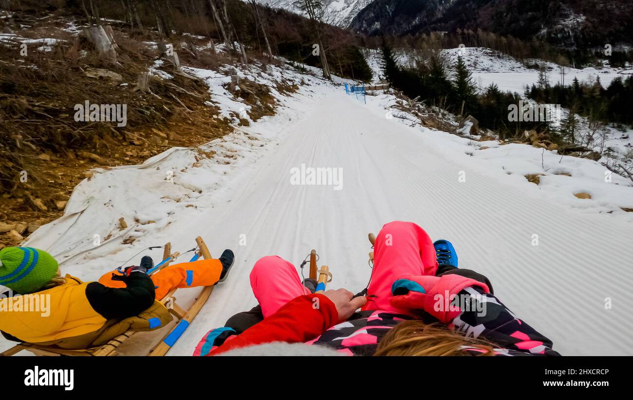Parent riding a kid on a sled, moving fast on the bumpy snow track ...