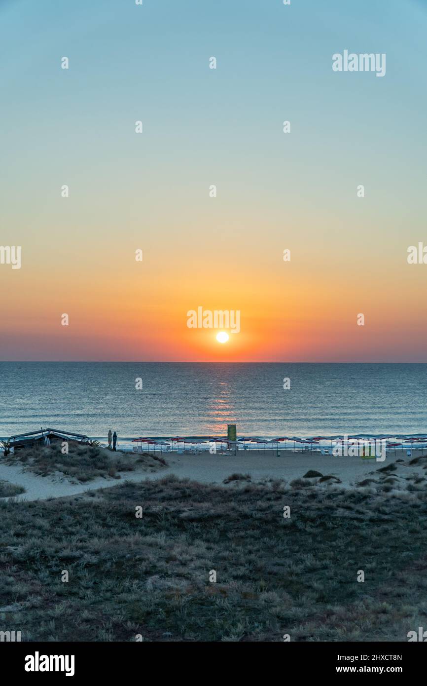 Amazing sunrise over the sand dunes on the shore with sun beds and ...