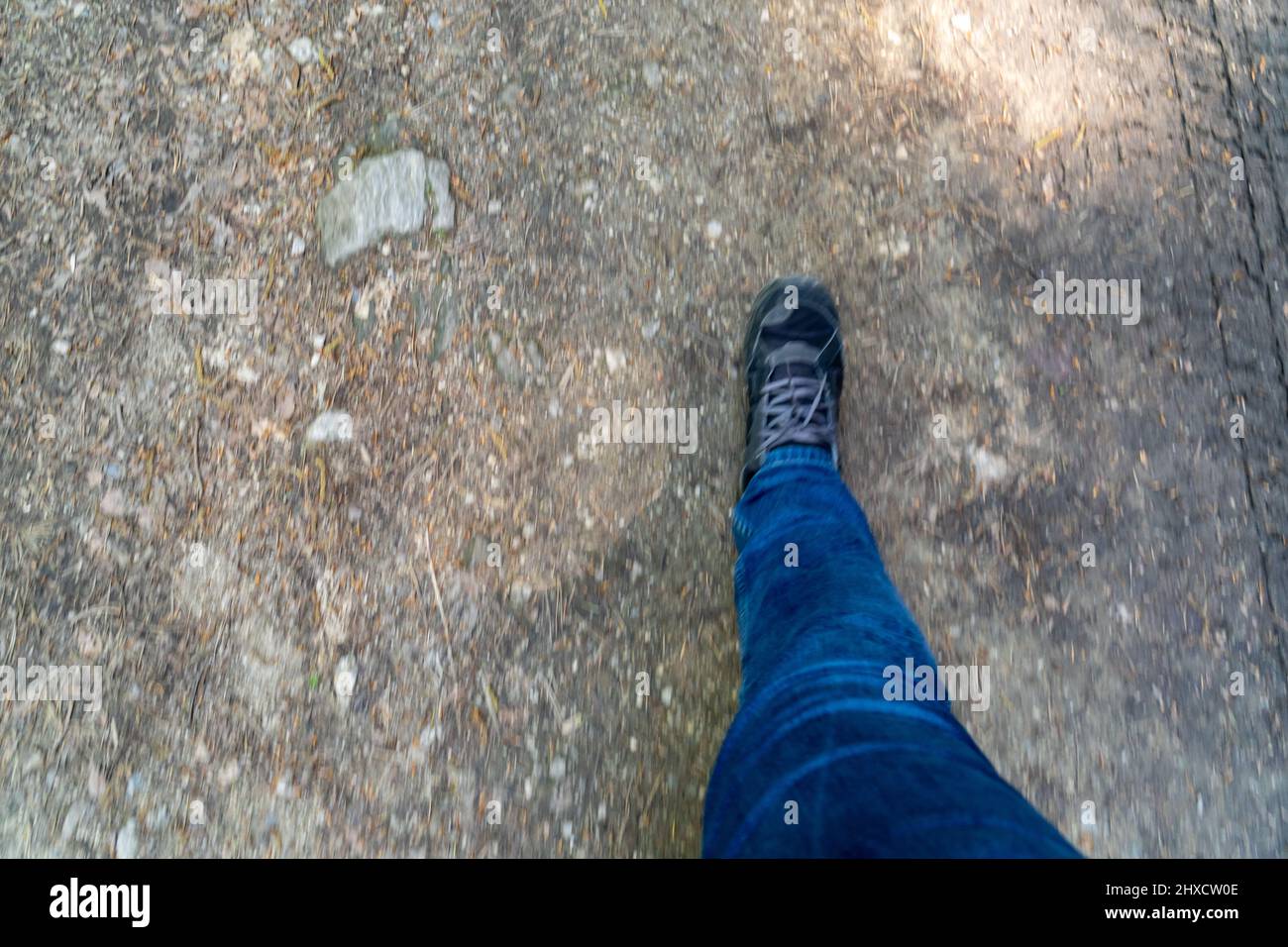 Top down view of a person wearing jeans and sneakers, walking on a ...