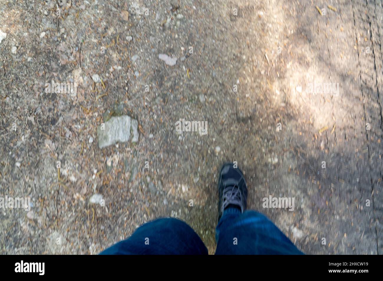 Top down view of a person wearing jeans and sneakers, walking on a ...