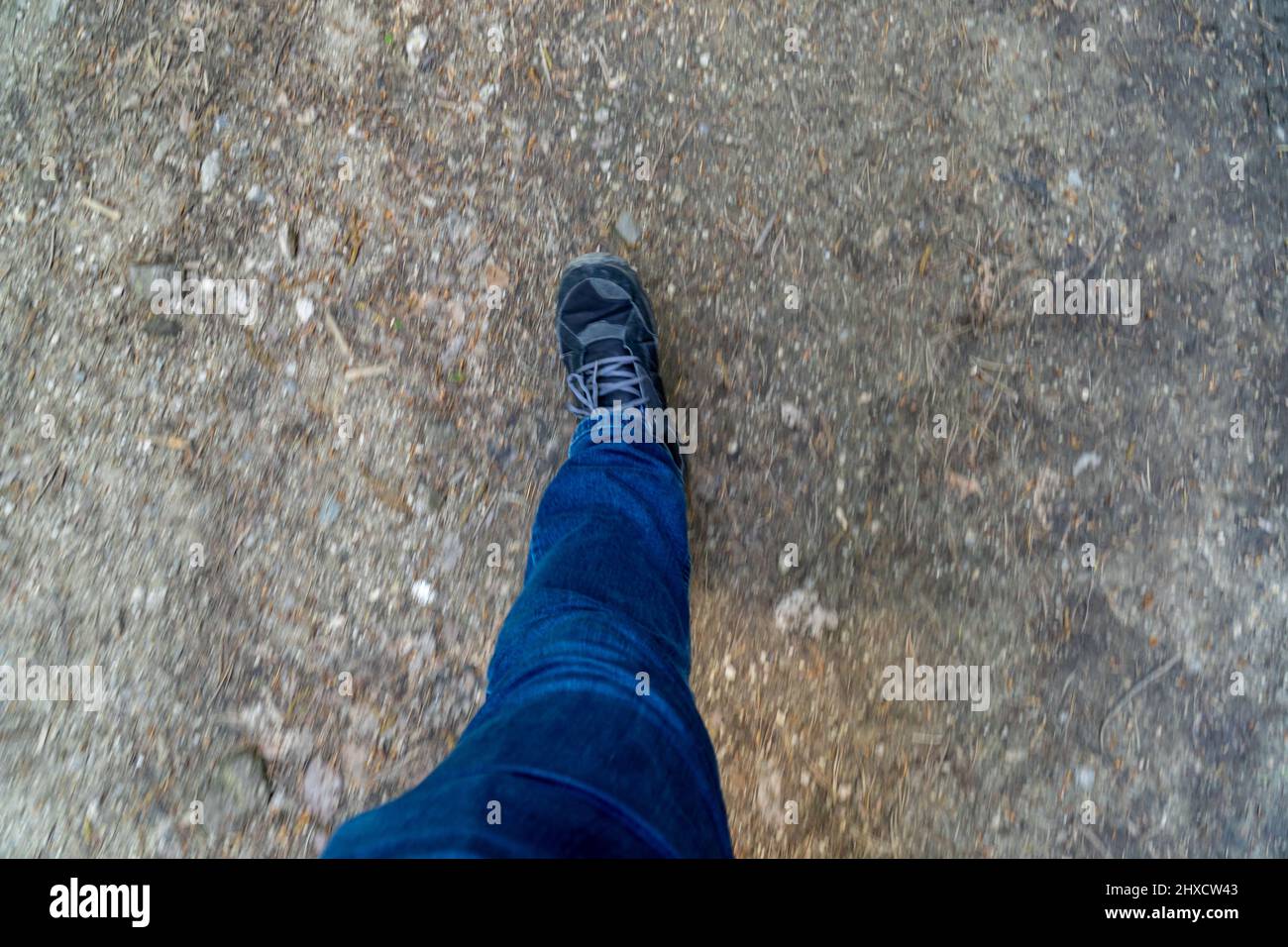 Top down view of a person wearing jeans and sneakers, walking on a ...