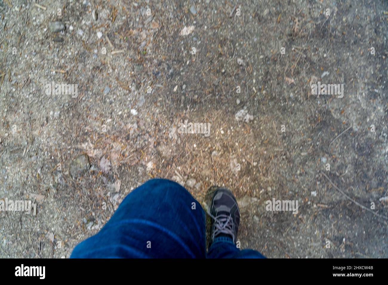 Top down view of a person wearing jeans and sneakers, walking on a ...