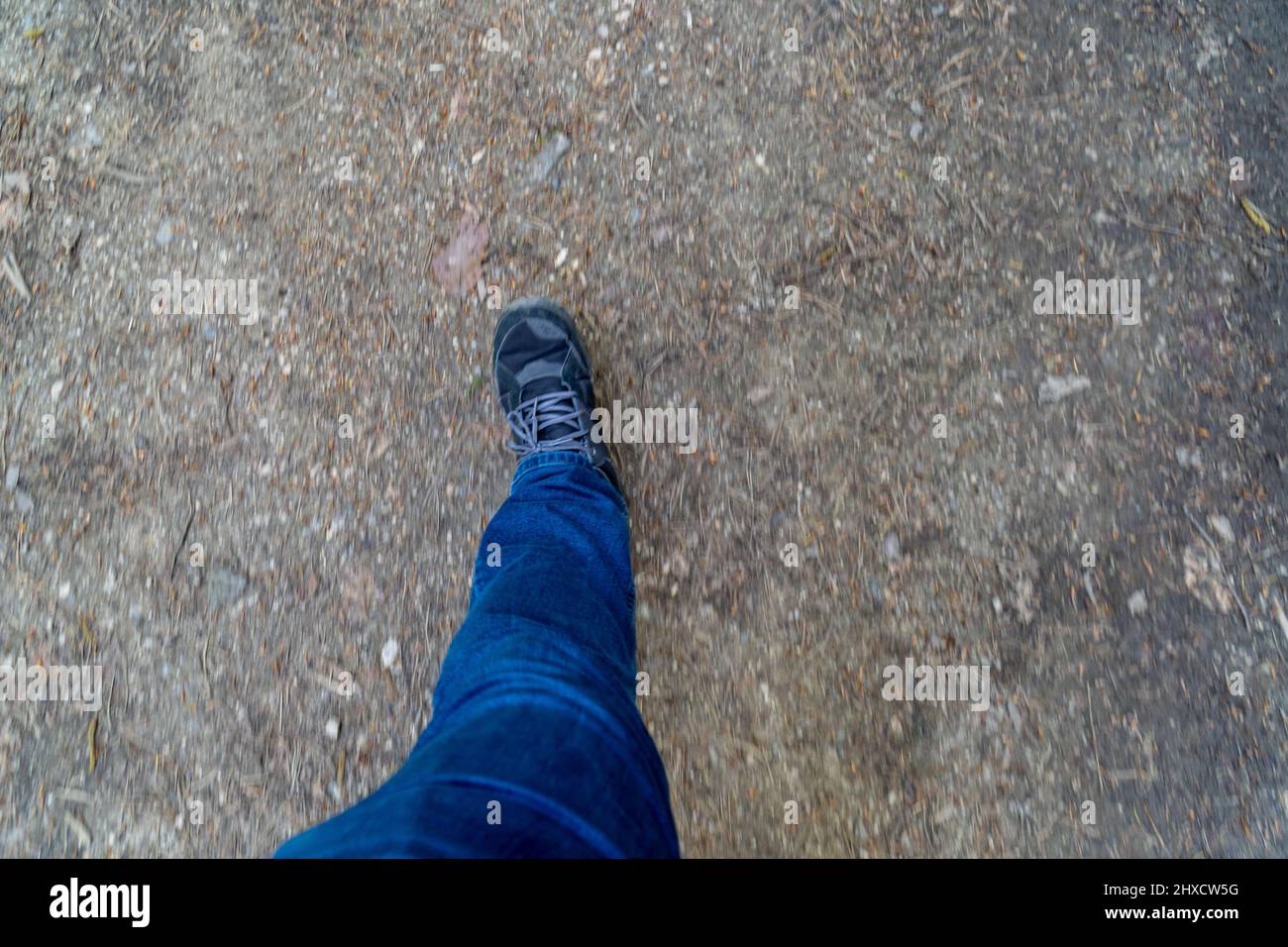 Top down view of a person wearing jeans and sneakers, walking on a ...