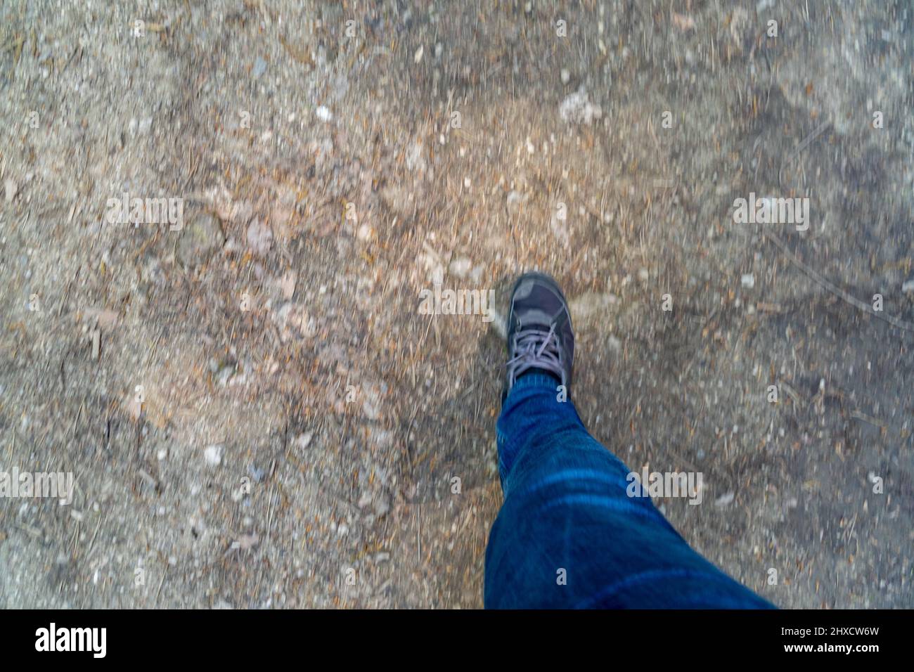 Top down view of a person wearing jeans and sneakers, walking on a ...