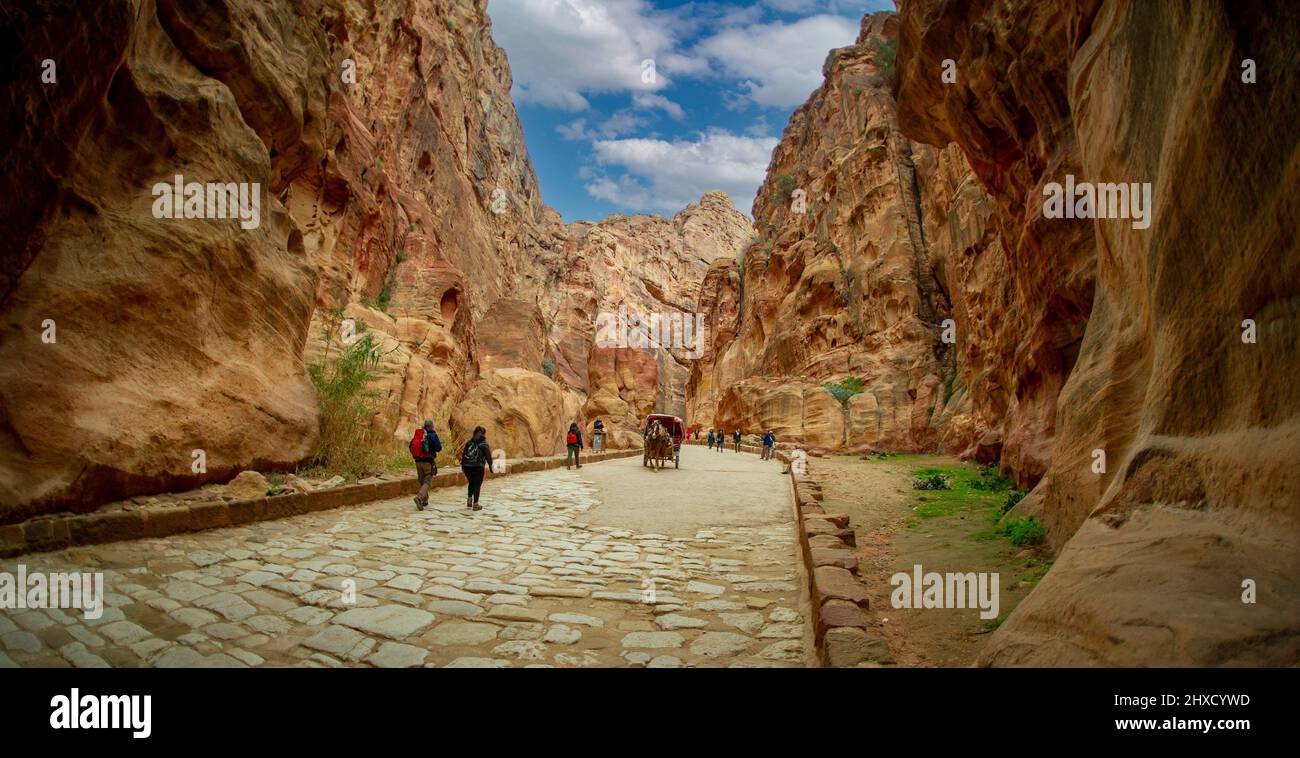 Tourists visiting Petra in Jordan walk or are helped by Bedouin carts ...