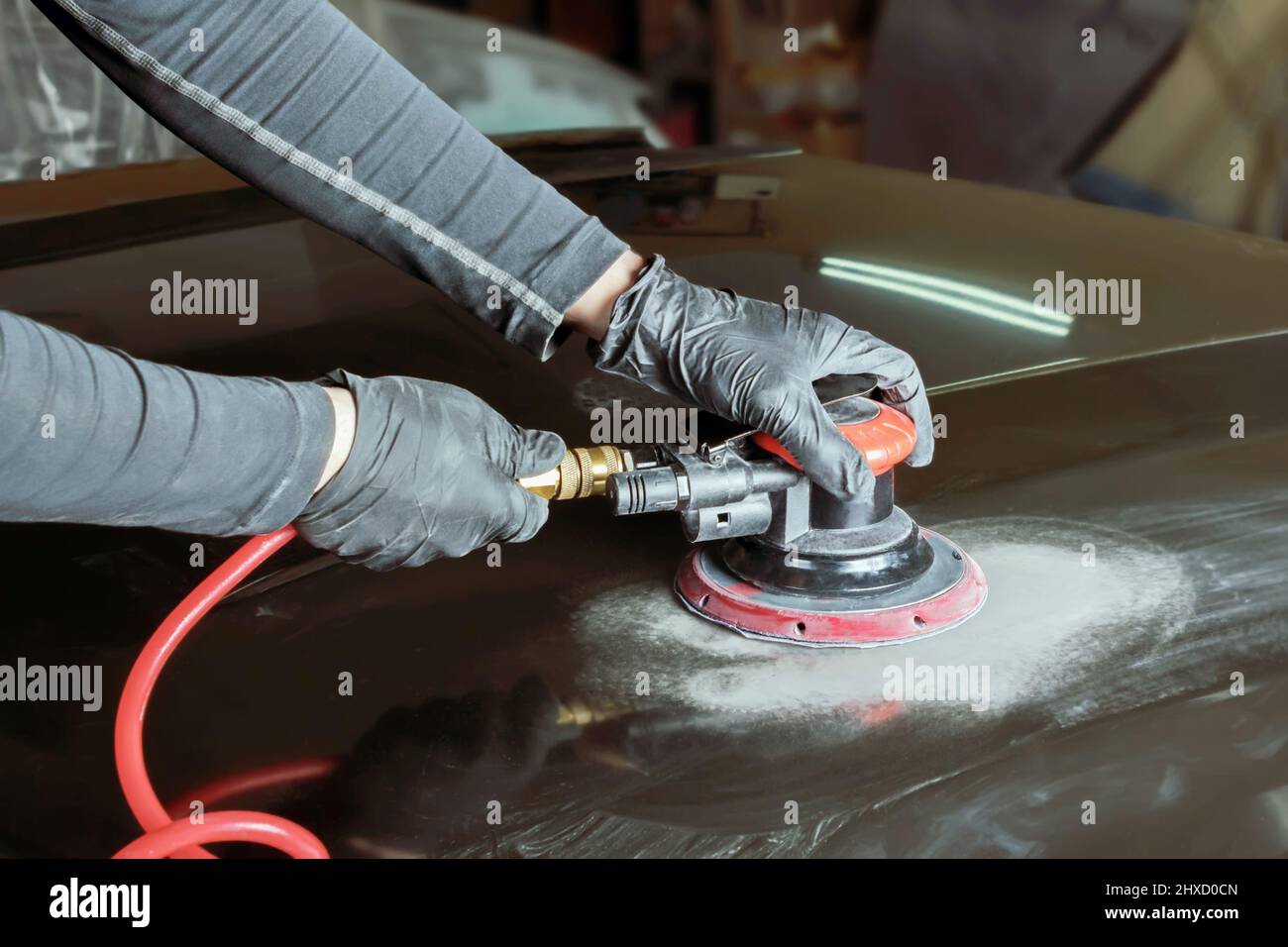 Hands of a painter who grinds a car for painting in a mechanical ...
