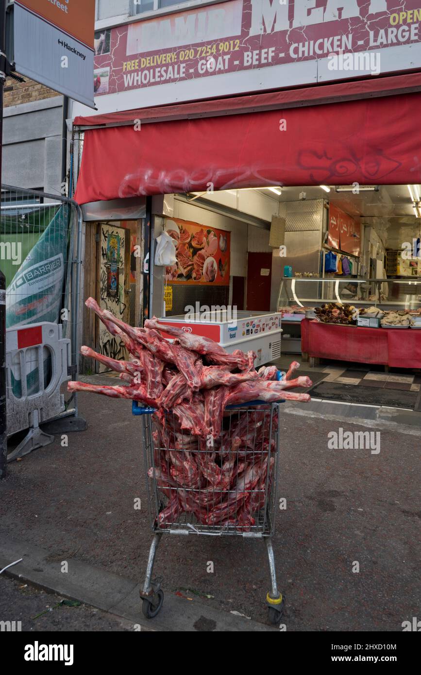Halal butcher carrying meat in a trolley to shop in Ridley Road market ...