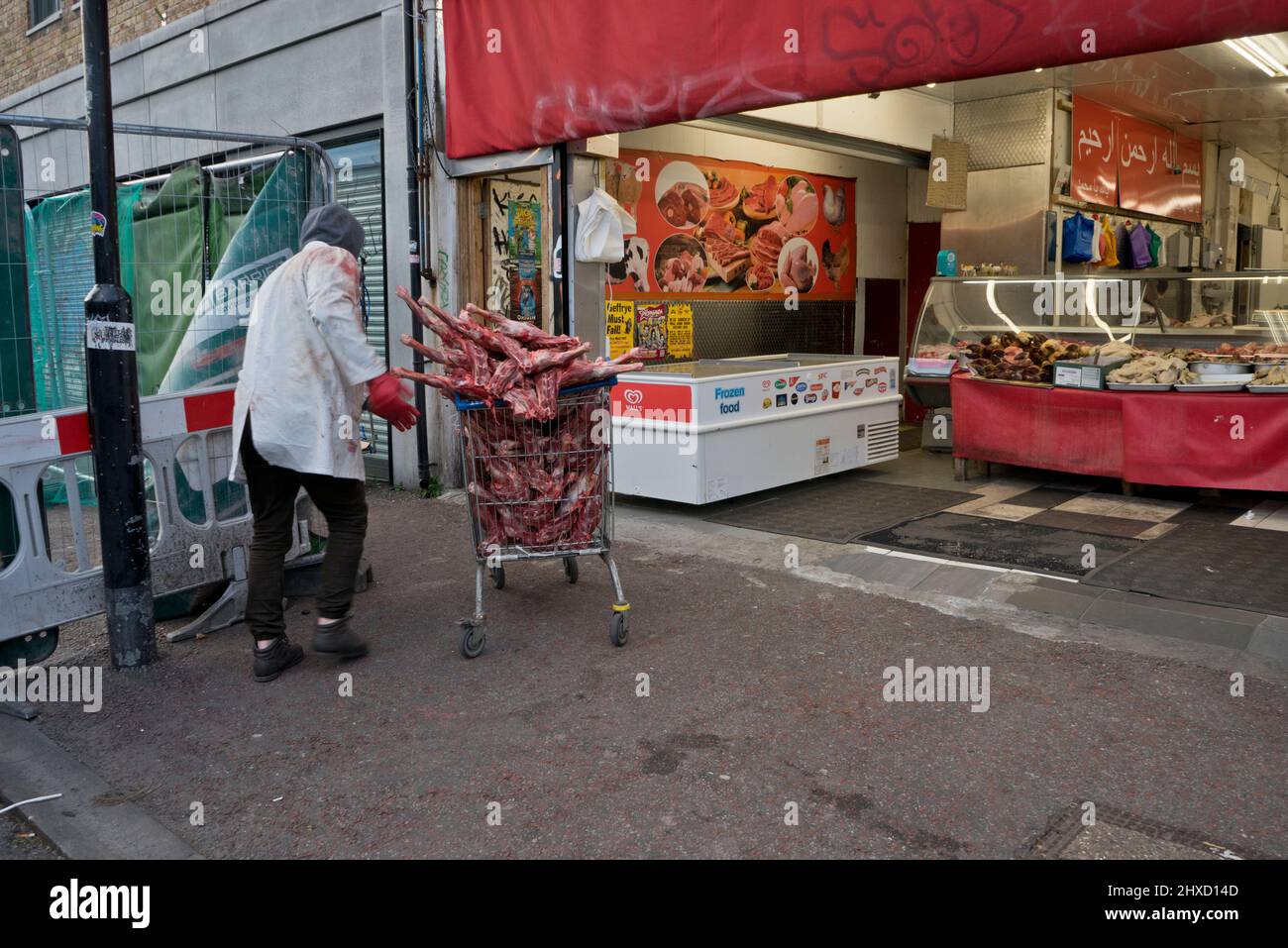Halal butcher carrying meat in a trolley to shop in Ridley Road market ...