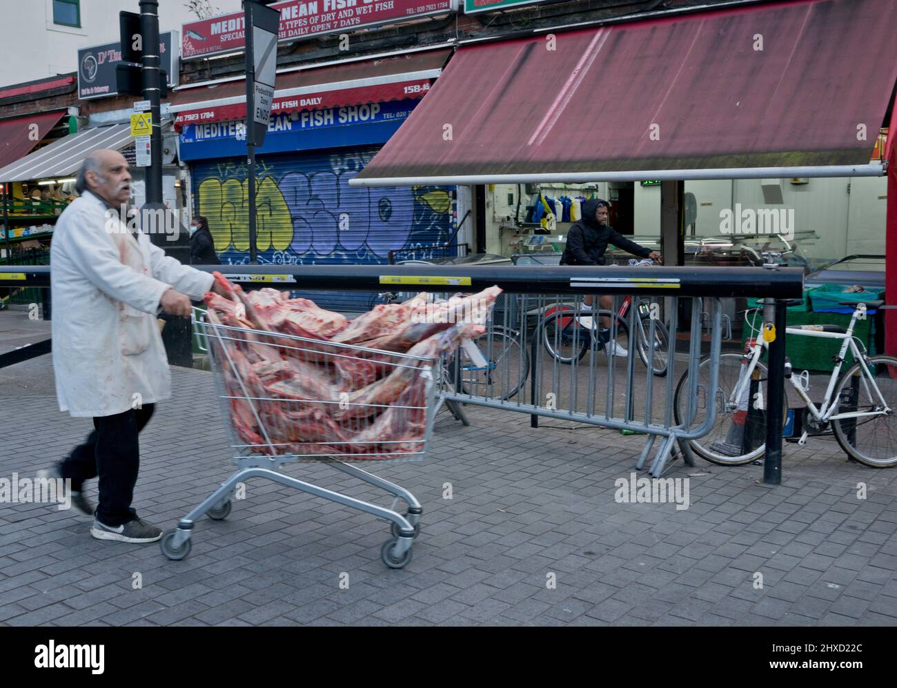Halal butcher carrying meat in a trolley to shop in Ridley Road market ...