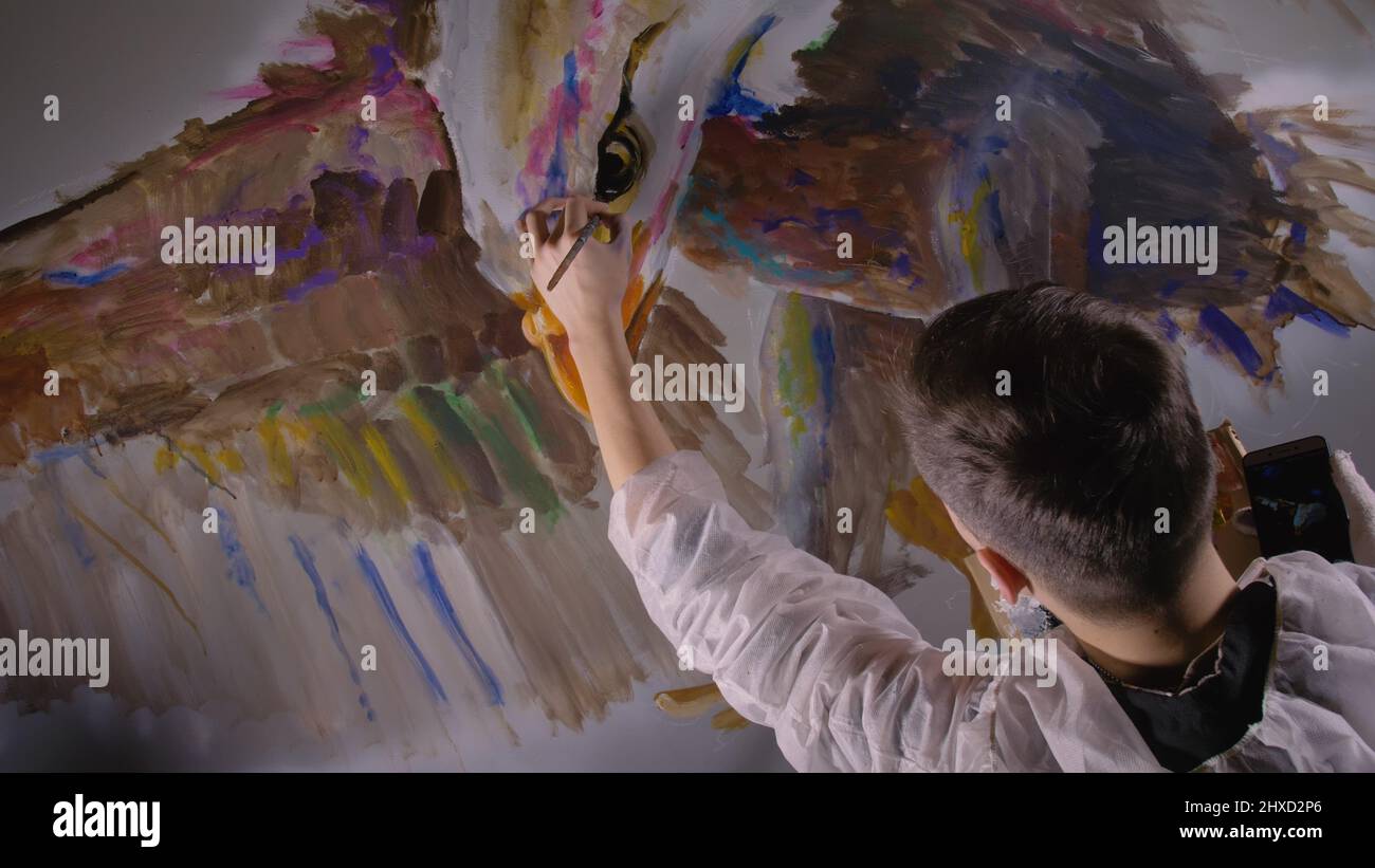 Artist designer draws an eagle on wall. Craftsman decorator paints ...