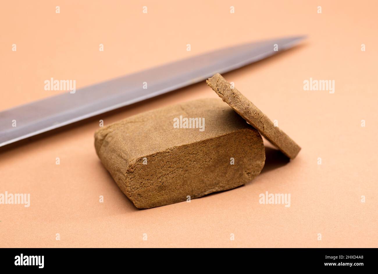two portion hashish tablet with knife blade, brown background Stock ...
