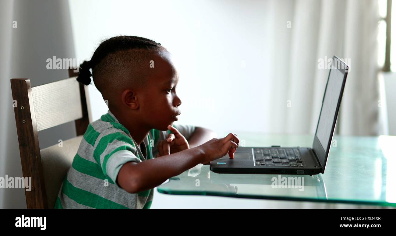Little boy browsing internet on laptop. Black African ethnicity kid ...