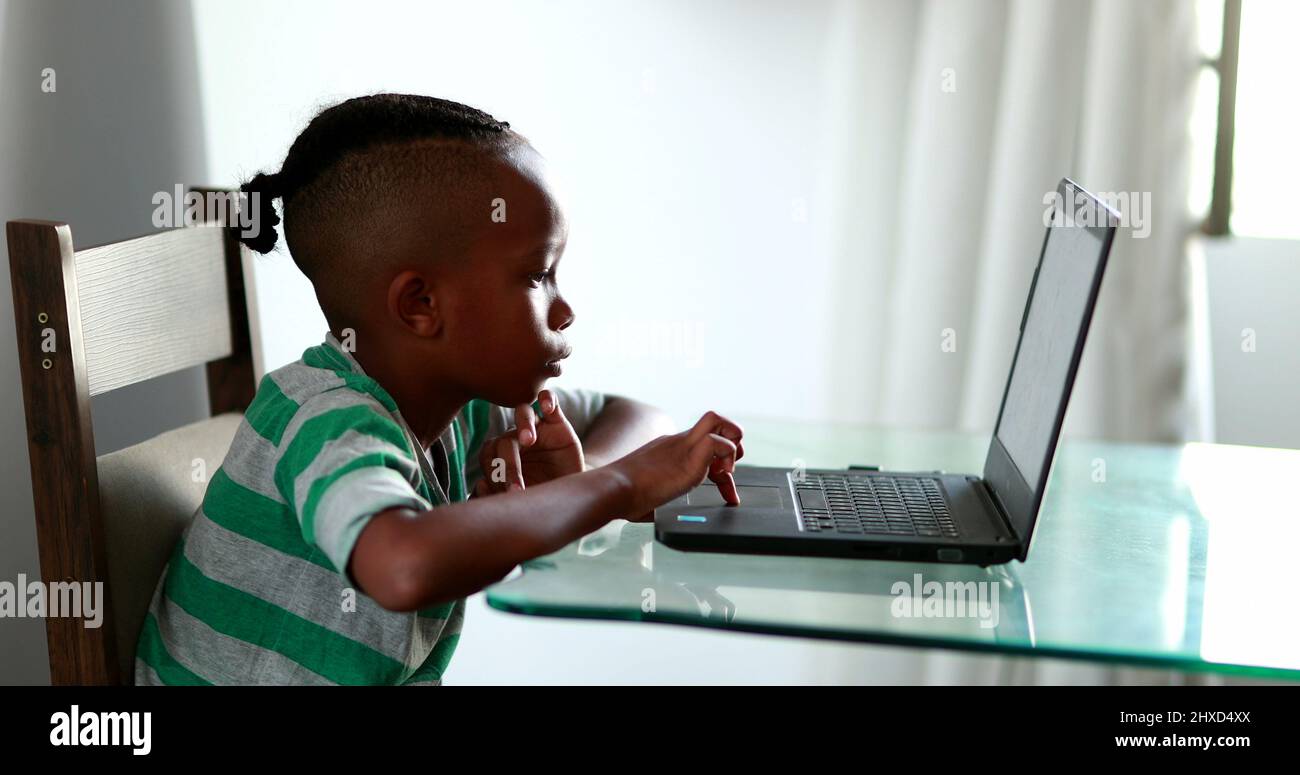 Little boy browsing internet on laptop. Black African ethnicity kid ...