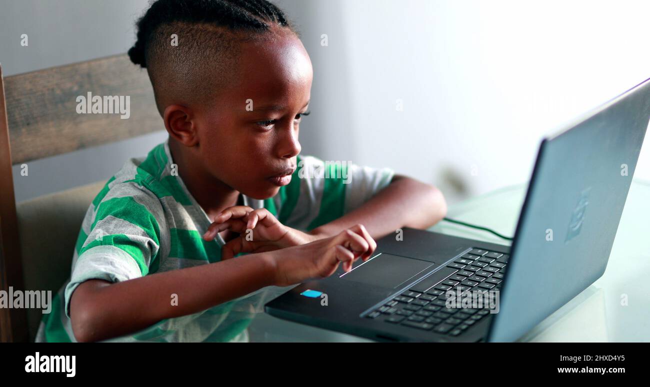 Little boy browsing internet on laptop. Black African ethnicity kid ...