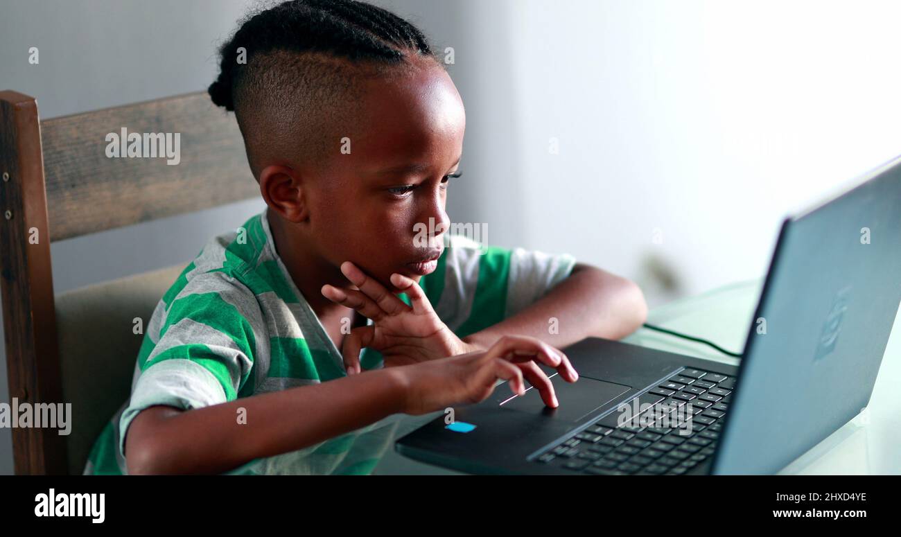 Little boy browsing internet on laptop. Black African ethnicity kid ...