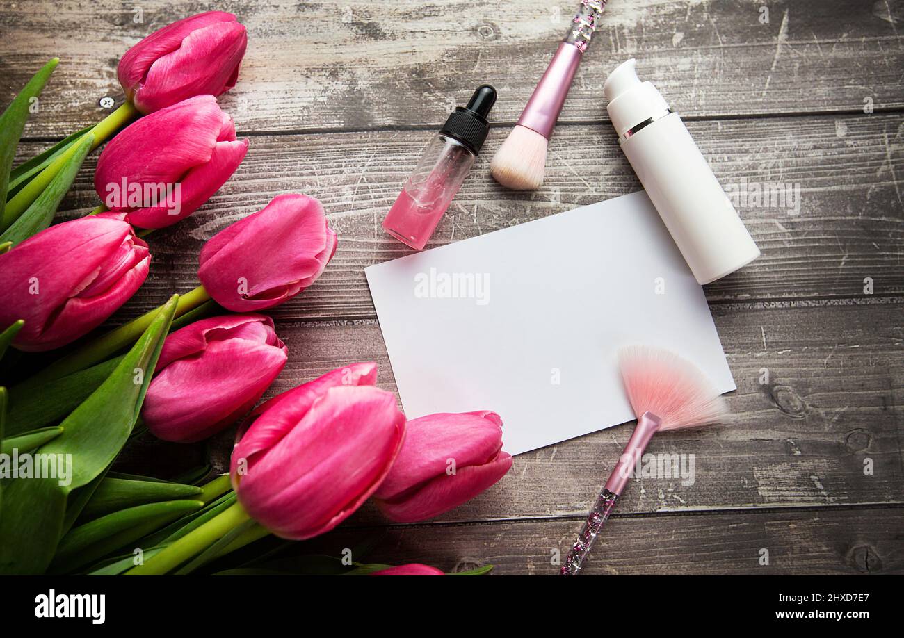 Feminine desk workspace with cosmetics, lipstick and tulip flowers on ...