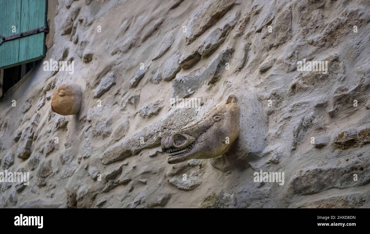 Masquen on stone wall in Aigne. The old village center has the shape of ...