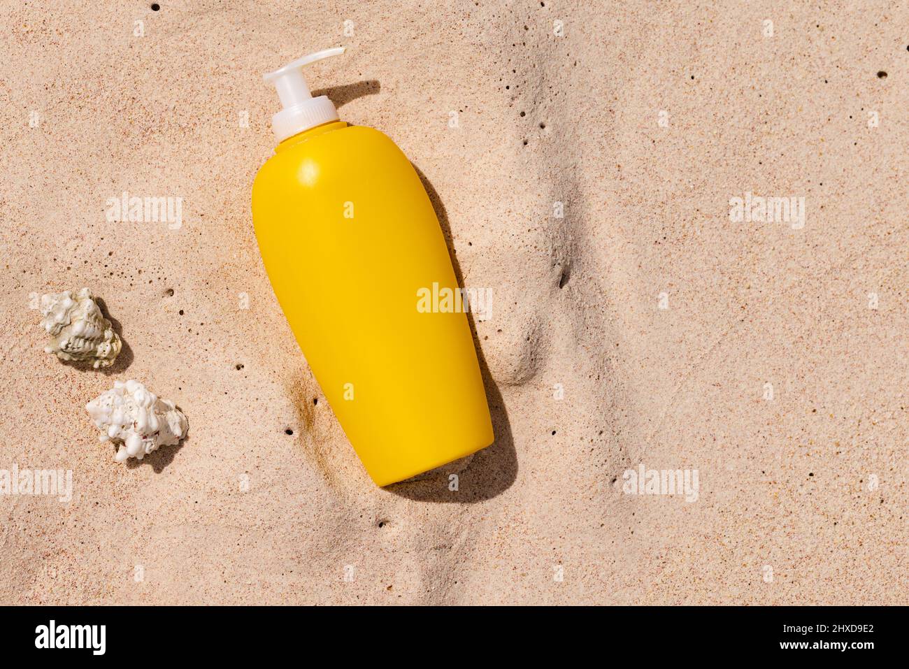 Yellow tube of suncream and seashells on the sand. UV and sunburn ...