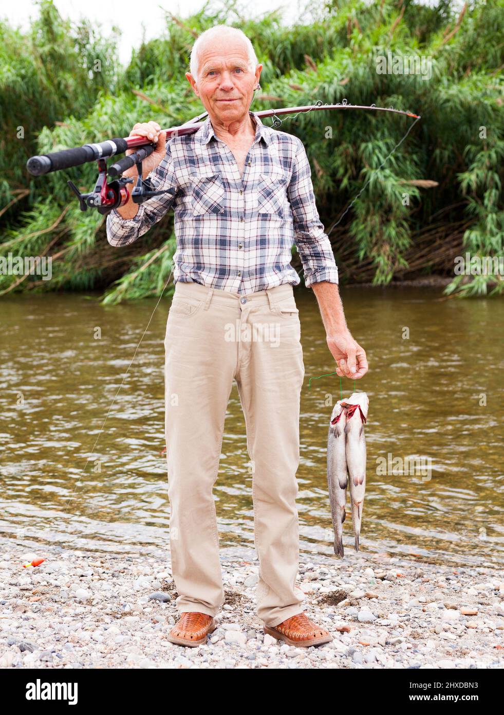 Fisherman posing with catch at riverside Stock Photo - Alamy