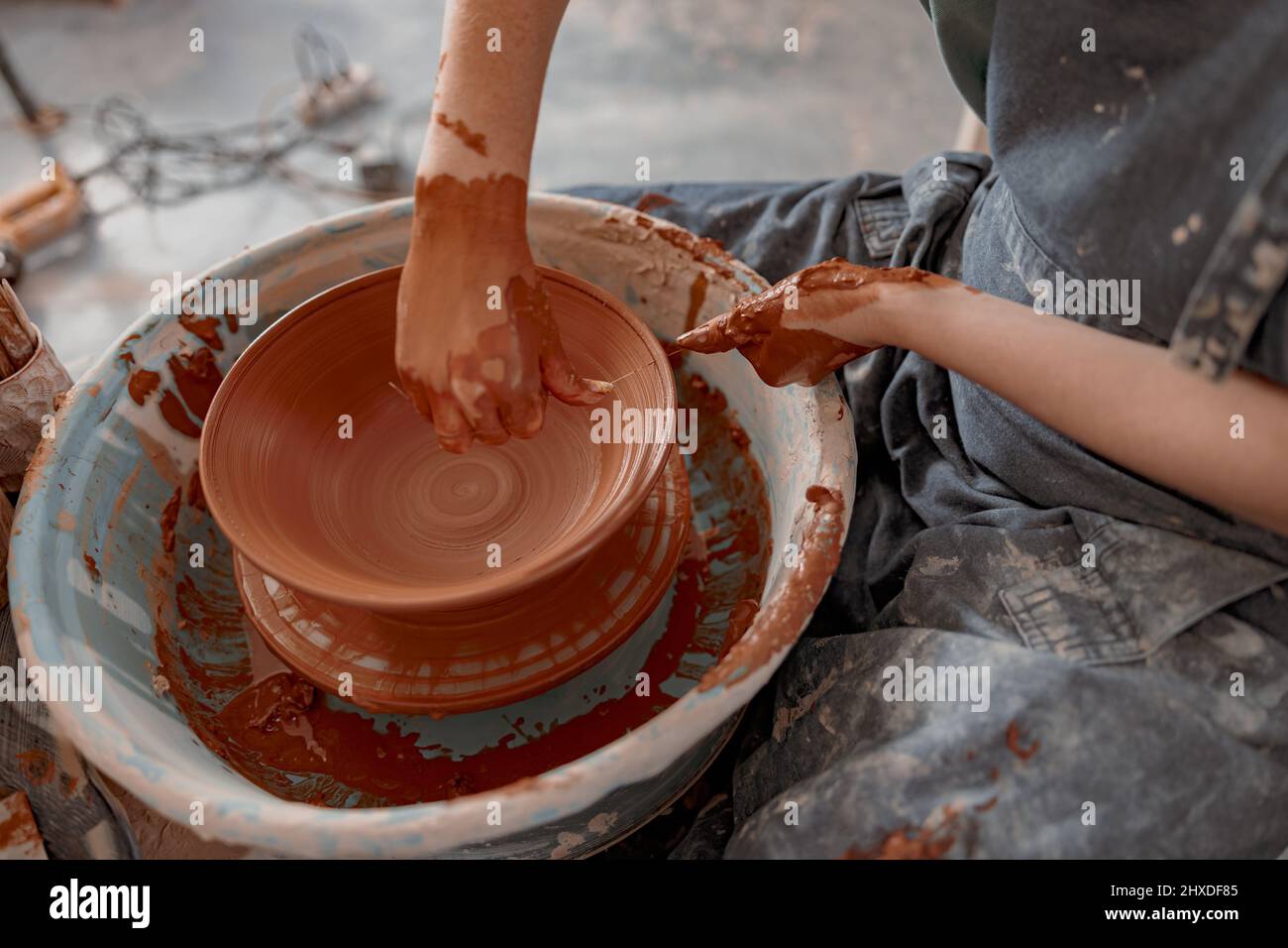 Skillful craftswoman creating earthen bowl on circle in art studio ...
