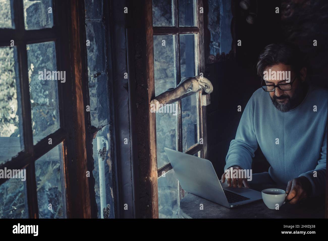 Handsome mature man working with laptop computer in the dark inside a ...