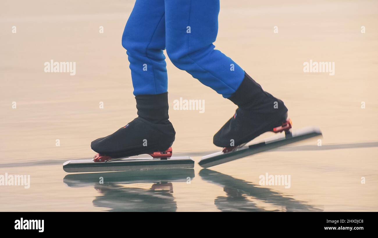 The child train on ice speed skating. The legs in skates close up. The ...