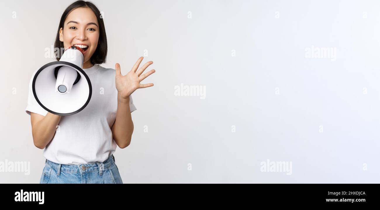 Happy asian woman shouting at megaphone, making announcement ...