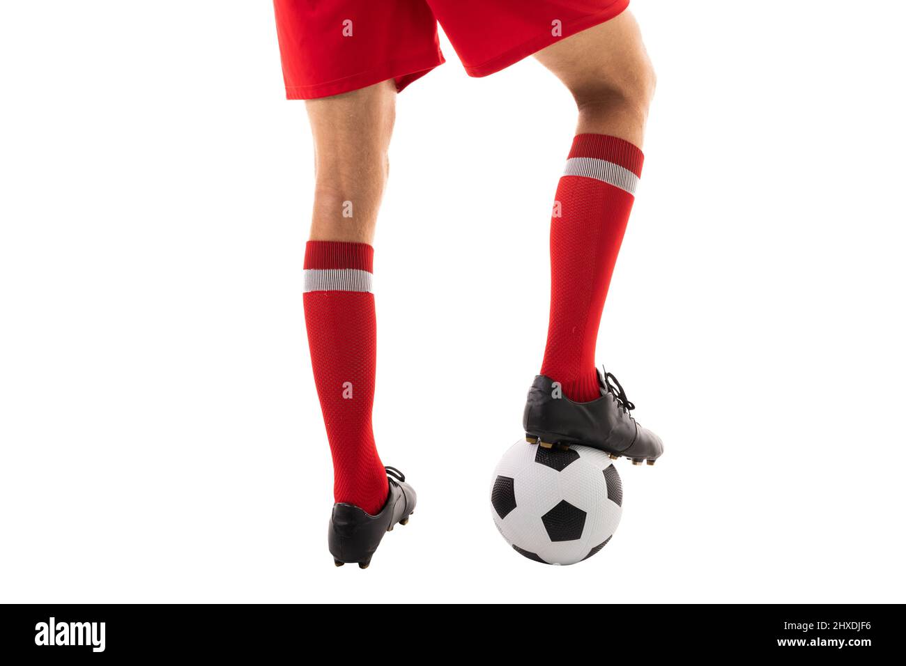 Low section of young male caucasian athlete stepping on soccer ball ...