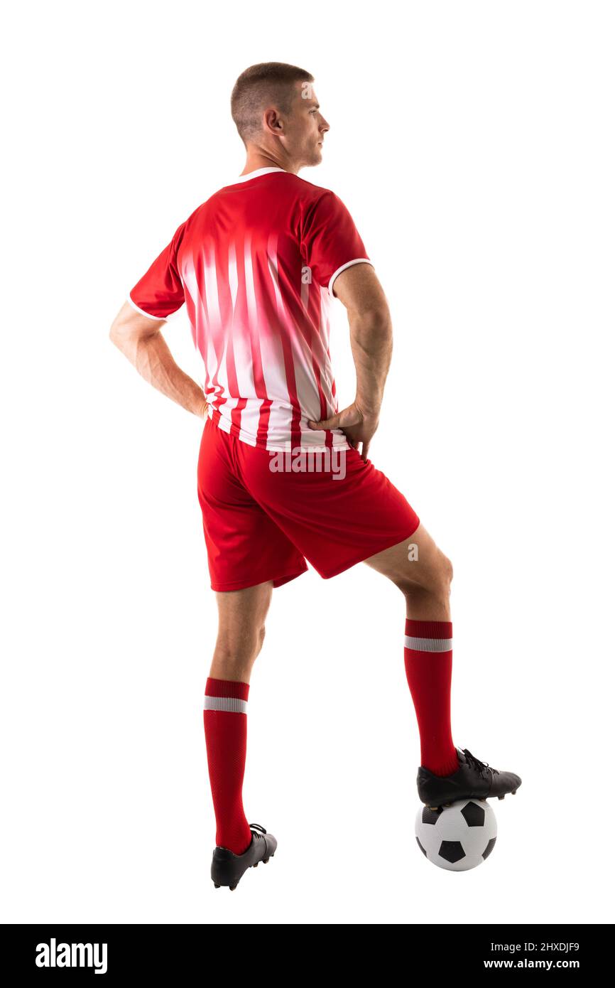 Full length rear view of young male soccer player stepping on ball over ...