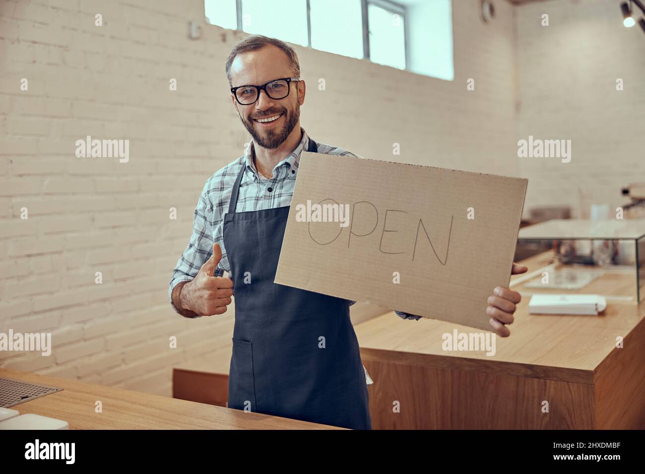 Cheerful man holding open sign and giving thumbs up Stock Photo - Alamy