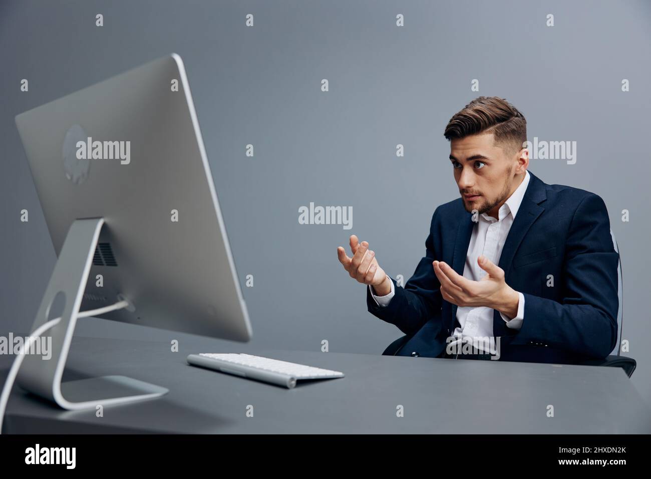 businessmen sitting at a desk in front of a computer Gray background ...