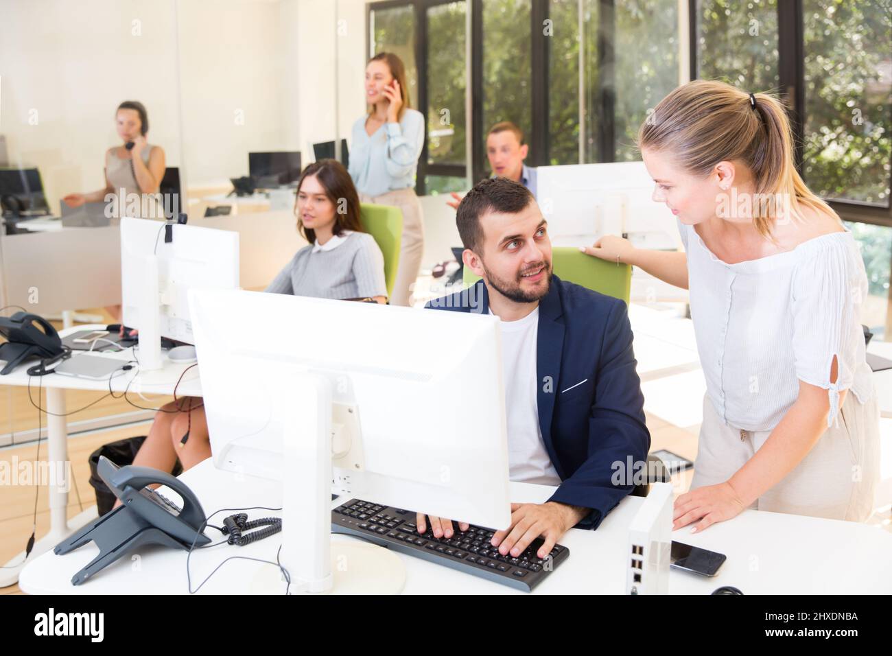 Friendly girl helping male colleague in work Stock Photo - Alamy