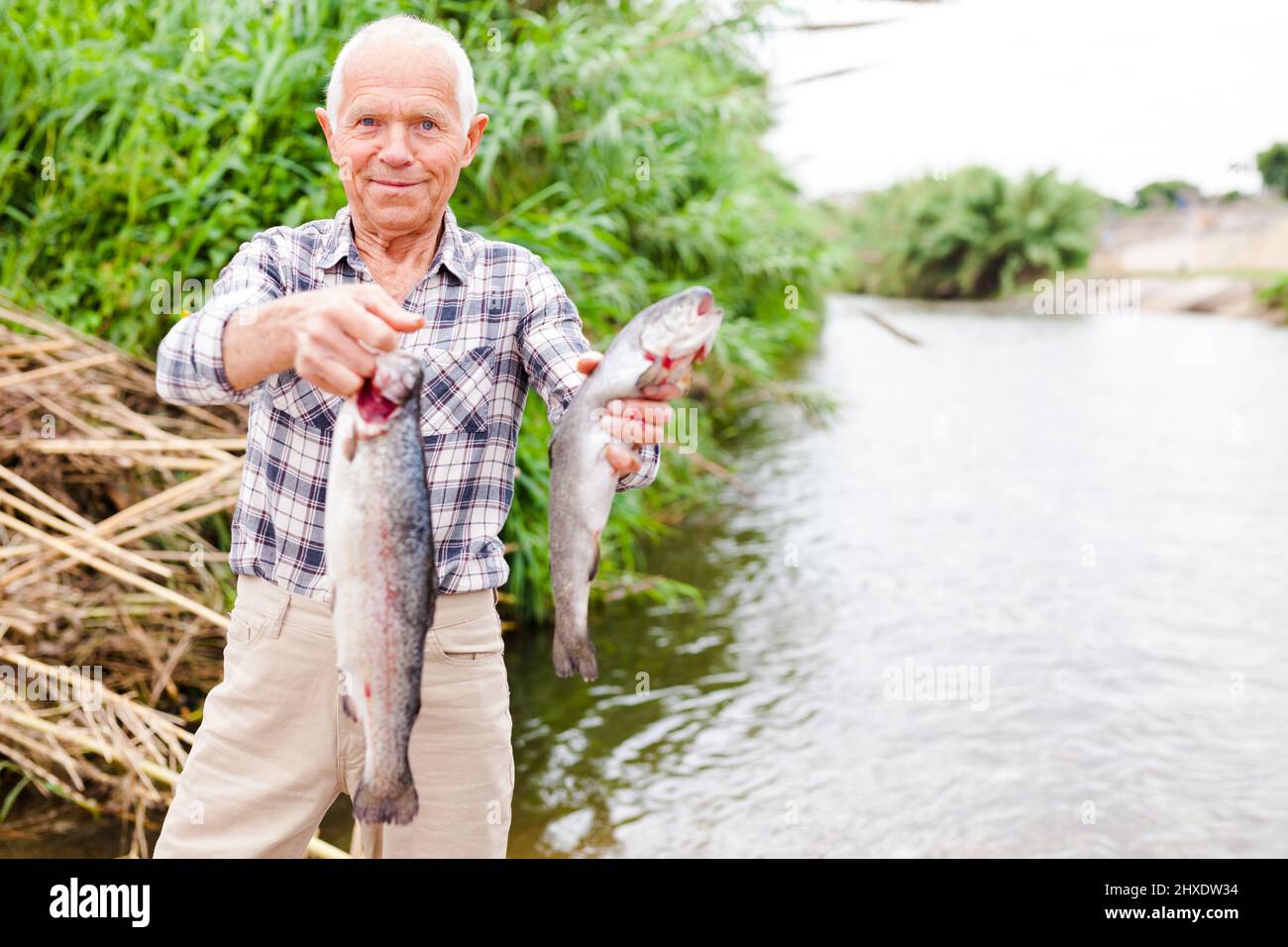 Fisherman posing with catch at riverside Stock Photo - Alamy