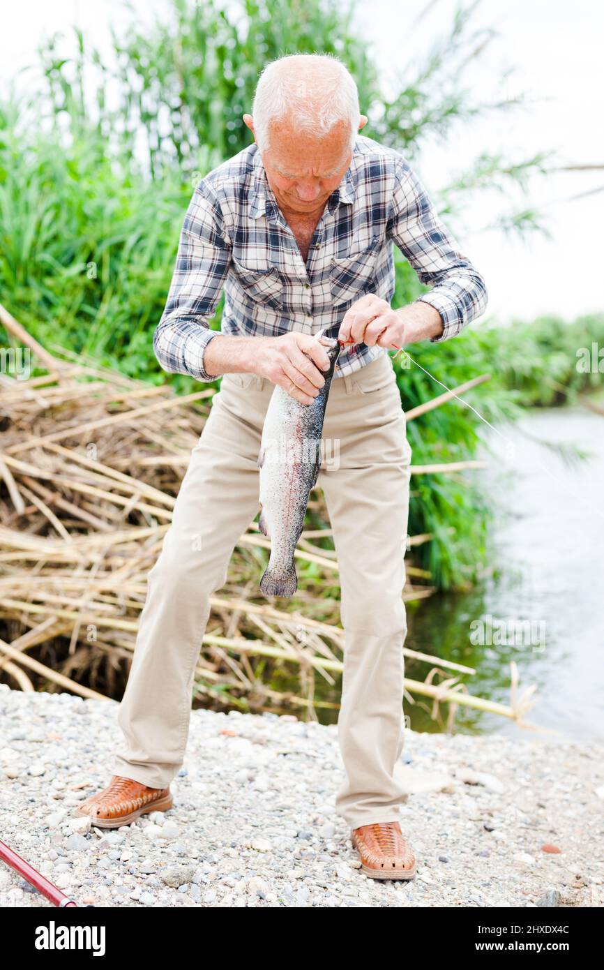 Fisherman pulling fish from river Stock Photo - Alamy
