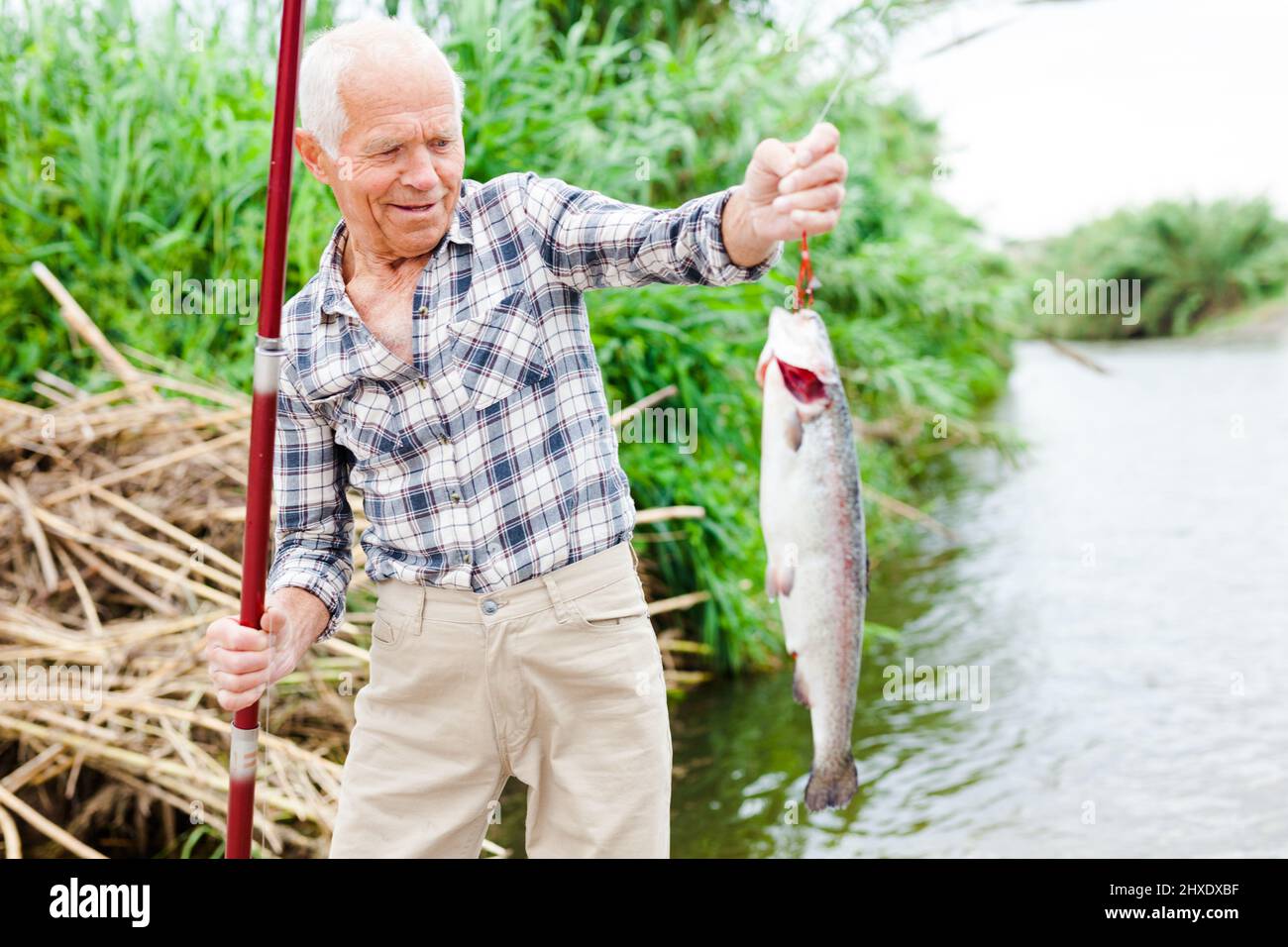 Fisherman pulling fish from river Stock Photo - Alamy