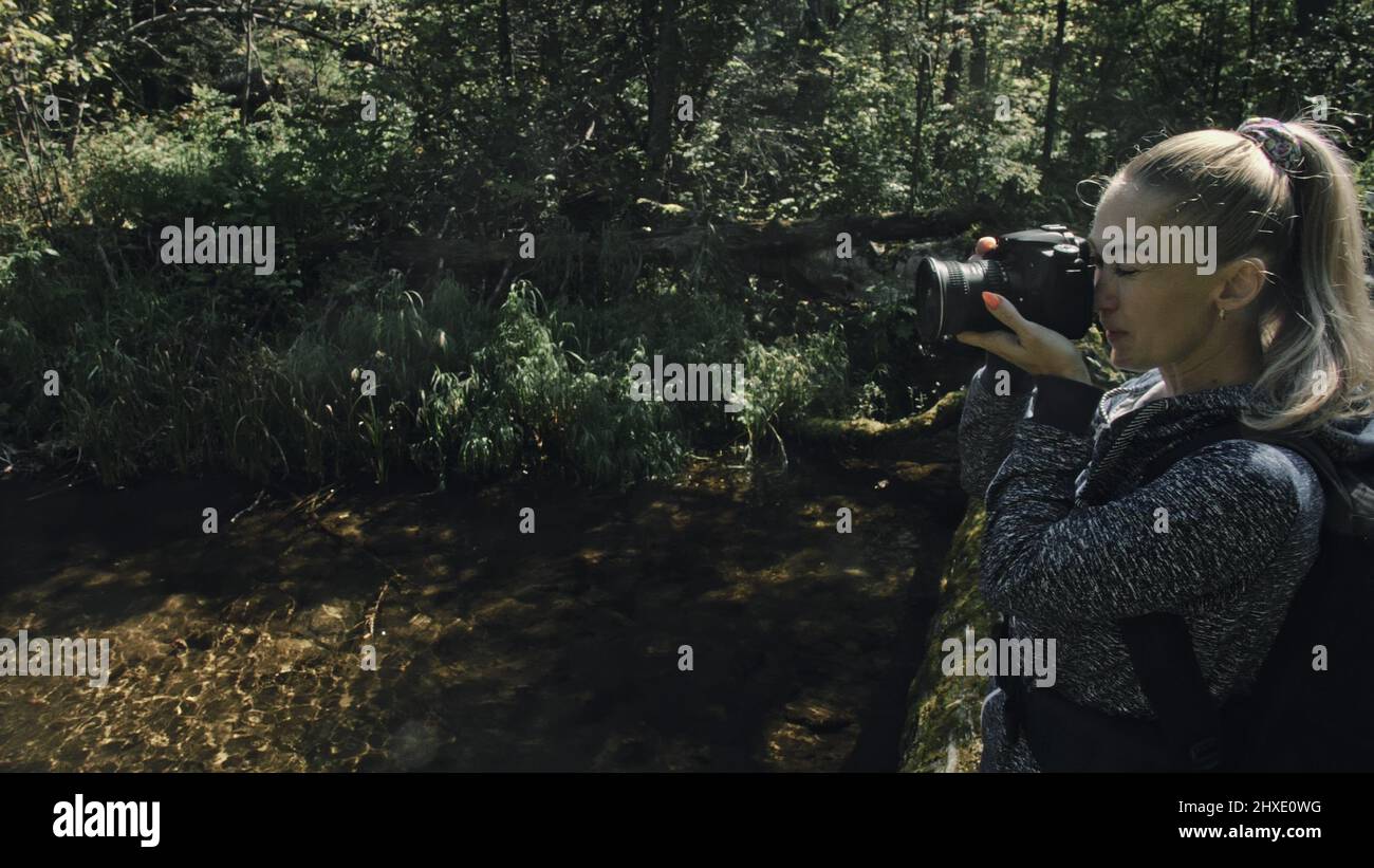 Traveler photographing scenic view in forest river. Wood bridge fallen ...