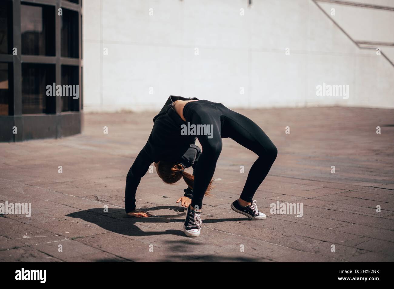 Flexible Woman doing advanced stretch techniques outdoors in the urban ...