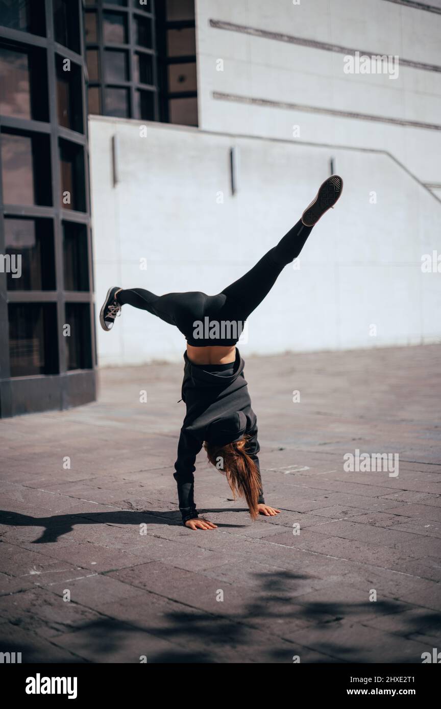 Woman doing advanced yoga outdoors in the urban area, side view ...