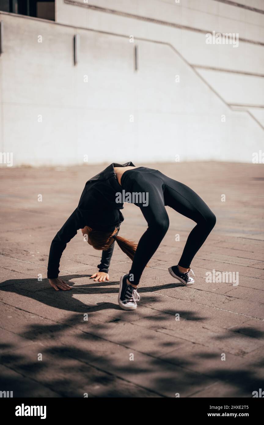Flexible Woman doing advanced stretch techniques outdoors in the urban ...