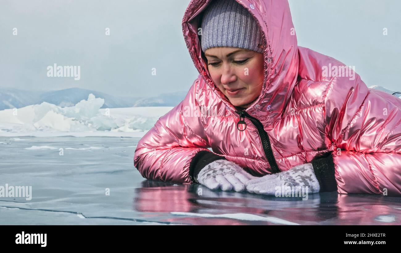 Girl walking on cracked ice of frozen lake Baikal. Woman traveler ...